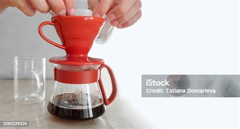 남자는 집에서 양조 V 60 그는 종이 필터를 세라믹 드립퍼에 넣고 뜨거운 물을 부어 커피를 쏟아 붓기위한 필터를 준비합니다 수증기에 대한 스톡 사진 및 기타 이미지