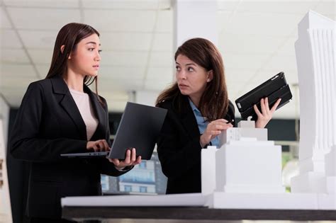 건축 소프트웨어를 사용하여 3d 건물 모델에 대해 논의하는 건축가 노트북을 들고 있는 엔지니어 건축 사무소에서 태블릿으로 작업합니다 태블릿 엔지니어링을 갖춘 디자이너