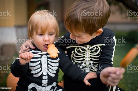 귀여운 아기 소녀와 해골 의상을 입은 어린 소년은 할로윈 과자를 먹는다 아기에 대한 스톡 사진 및 기타 이미지 아기 할로윈