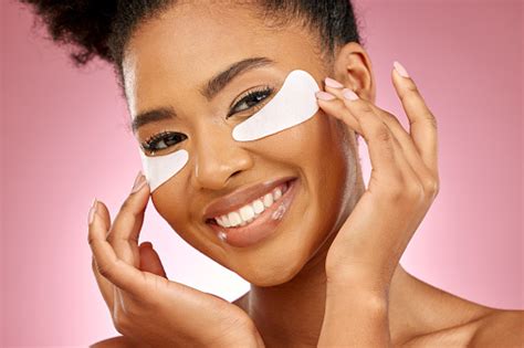 여성 미소 그리고 핑크색 배경의 제품으로 스튜디오 초상화에서 스킨케어를 위한 안대 소녀 모델 및 손으로 얼굴 셀프 케어 자연스러운 피부 광채 또는 건강을 위한 미적 20