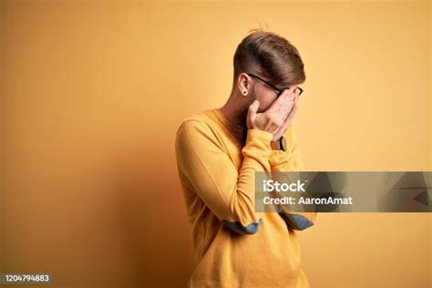 울고있는 동안 손으로 얼굴을 덮고 슬픈 표정으로 노란색 고립 된 배경위에 안경을 쓰고 수염을 기르는 잘 생긴 아일랜드 빨간 머리 남자 우울증 개념 가리기에 대한 스톡 사진