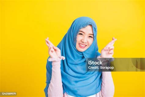 아시아 무슬림 아랍 행복한 아시아 아름다운 젊은 여성의 초상화 이슬람 종교 착용 베일 히잡 그녀는 미소와 잡고 손가락이 행운을 위해 교차 노란색 배경에 고립 된 스튜디오