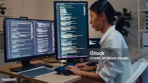 Young Asian Woman Software Developers Using Computer To Write Code Sitting At Desk With Multiple