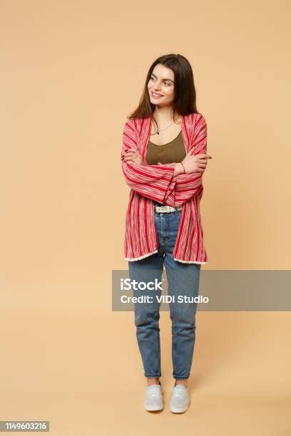 옆을 찾고 캐주얼 복장에 웃는 젊은 여자의 초상화 손을 잡고 스튜디오에서 파스텔 베이 지 배경에 고립 교차 사람들은 진심으로 감정 라이프 스타일 개념입니다 복사 공간을 모의