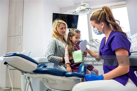 여성 치과 의사는 환자의 치아를 검사하고 어머니는 치과 진료소에서 그녀를 지원합니다 미소에 대한 스톡 사진 및 기타 이미지 미소 치과 의사 3 명 Istock
