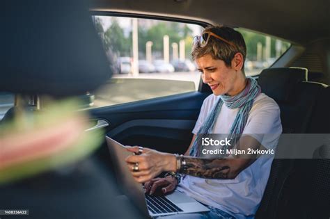 여름날 노트북 컴퓨터에서 일하는 자동차 뒷좌석에 앉아있는 성숙한 여성 백인 여성 한 명과 짧은 회색 머리 현대 관리자 또는 캐주얼 카피 공간을 착용하는 도로의 비즈니스