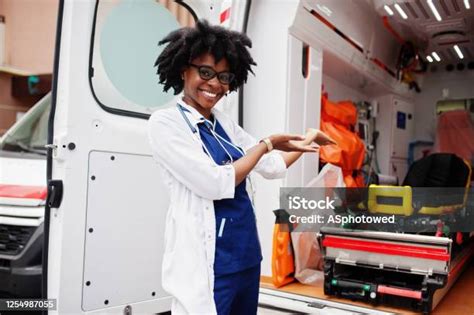 구급차 차 앞에 서 있는 얼굴 보호 의료 마스크를 착용한 아프리카계 미국인 여성 구급대원 간호사에 대한 스톡 사진 및 기타