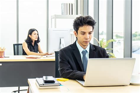 책상에 앉아 있는 젊은 아시아 사업가와 직장인을 배경으로 노트북을 작업하는 사업가 20 24세에 대한 스톡 사진 및 기타 이미지 20 24세 2명 35 39세