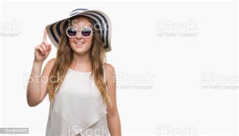 선글라스와 여름 모자를 착용 하는 젊은 금발의 여 자가 놀 생각 또는 행복 한 얼굴을 가리키는 손가락 질문 번호 하나 가리키기에 대한 스톡 사진 및 기타 이미지 Istock