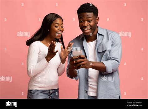 Handsome Black Guy Showing His Girlfriend Something On Smartphone Stock