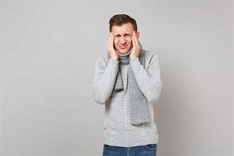 회색 스웨터 스카프 데 두통에 지친된 젊은 남자 사원 회색 벽 배경에 고립에 손을 넣어 건강 한 생활양식 아픈 아픈 질병 치료 추운 계절 개념 복사 공간을 비웃는 다 가을에