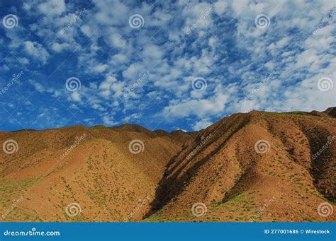 Scenic Vista Of A Mountain Range With Sparse Grass And Trees In The