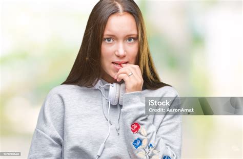 강조 하 고 손톱을 물어 뜯고 입에 손을 긴장을 찾고 격리 된 배경 위에 헤드폰을 착용 하는 젊은 아름 다운 백인 학생 여자