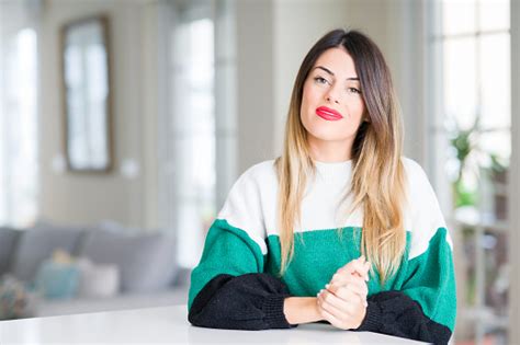 젊은 아름 다운 여자는 함께 집에서 손에 겨울 스웨터를 입고 손가락과 편안 하 고 쾌활 한 미소 교차 성공과 낙관적 사업가에 대한 스톡 사진 및 기타 이미지 Istock