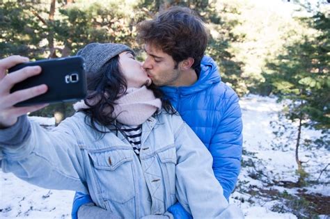 Premium Photo Young Couple Kissing While Taking Selfie With Mobile