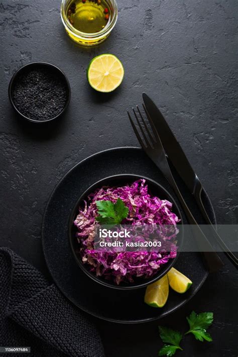 어두운 콘크리트 배경에 세라믹 플레이트에 올리브 오일 라임 및 검은 참 깨와 보라색 북경 양배추의 샐러드 김치에 대한 스톡 사진