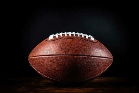 American Football Ball On A Wooden Table Against A Black Background