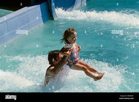 Father And Daughter Enjoying A Giant Water Slide Splashing Into Water