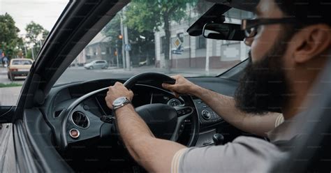 각진 측면보기 현대 캐주얼 수염 난 남자 안경 시계 및 티셔츠를 착용하고 차를 운전합니다 운전자의 손을 닫습니다 사진 Unsplash의 수송 이미지