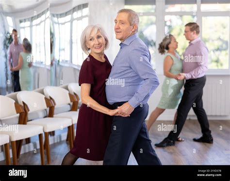 Pairs Of Mature Amateur Dancers Enthusiastically Performs Romantic Tango Dance In Dance Salon