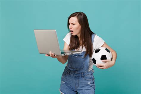 파란색 청록색 벽 배경에 고립 된 노트북 Pc 컴퓨터를 사용 하 여 축구 공을 들고 당황 젊은 여자 축구 팬 사람들의 감정 스포츠 가족 레저 라이프 스타일 개념입니다 복사