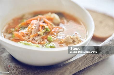 테이블 위에 놓인 하얀 접시에 담긴 야채와 고기로 만든 건강하고 맛있는 수프와 복사 공간이 있는 빵의 옆모습 브로콜리 당근 고기를 곁들인 밝은 수프 빵과 함께 접시에 담겨