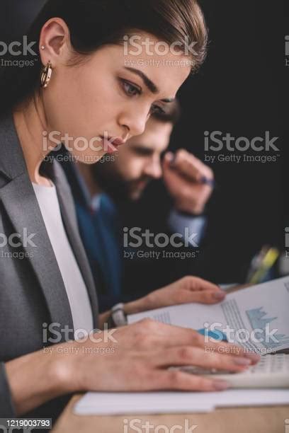 검정 색 배경에 동료 근처 종이에 계산기 및 차트와 함께 작업 하는 데이터 분석가의 선택적 초점 2명에 대한 스톡 사진 및 기타