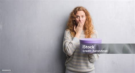 상자 덮개 입 실수 두려움의 표현에 대 한 수치와 충격을 손으로 잡고 회색 그런 지 벽에 빨강 머리 젊은 여자는 침묵 비밀 개념에에서 무서 워 가리기에 대한 스톡 사진 및