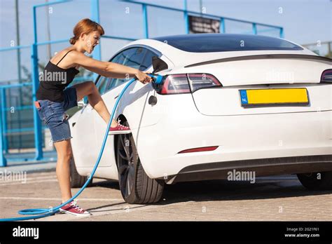 Girl Having Trouble Removing A Charging Cable From Her Electric Car Stock Photo Alamy