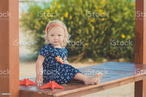 금발 머리와 분홍색 애플 뺨 완전 세련 된 드레스를 입고 모래의 아름 다운 해변에서 포즈 여름 시간 휴가 즐기는 귀여운 아가 건강한 생활방식에 대한 스톡 사진 및 기타