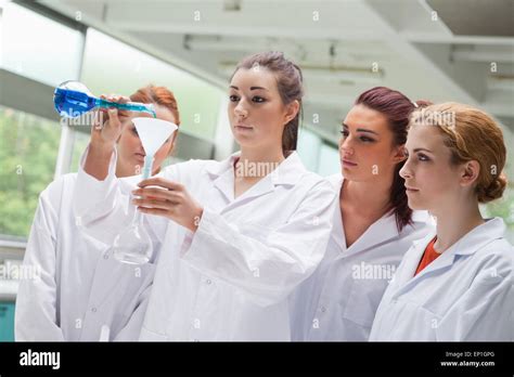 Female Science Babes Pouring Liquid In A Flask Stock Photo Alamy