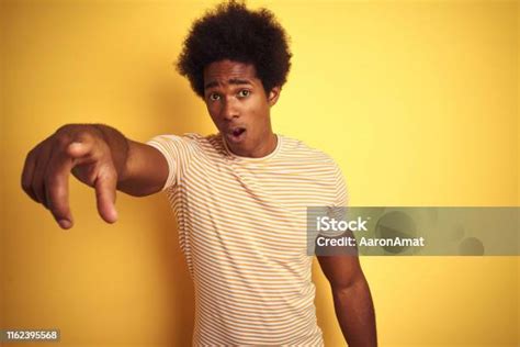고립 된 노란색 배경 위에 서있는 줄무늬 티셔츠를 입은 미국 남자가 불쾌하고 카메라에 좌절하고 화가 나서 분노합니다 T 셔츠에 대한 스톡 사진 및 기타 이미지 Istock