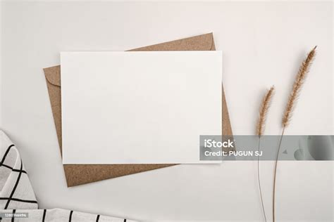 갈색 종이 봉투에 흰 종이를 비우고 검은 색 격자 패턴이있는 붉은 여우 꼬리 마른 꽃과 흰색 천 수평 빈 인사말 카드의 모형