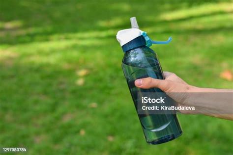 남자의 손은 자연 배경에 플라스틱 재사용 가능한 스포츠 물병을 보유하고 있습니다 텍스트에 대한 여유 공간입니다 환경 보호의 개념 자연을 저장 생태 플라스틱 무료 제로 폐기물