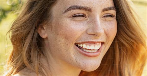 주근깨가 있는 행복한 아름다운 여자가 웃고 있고 화창한 날에 피는 정원에서 포즈를 취하고 있다 사진 Unsplash의 청년 성인 이미지