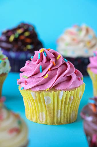 집에서 만든 핑크 아이싱과 개별 바닐라 컵 케이크의 클로즈업 이미지 종이 케이크 케이스에 컵 케이크 버터 아이싱 파이프 소용돌이와 수백 수천 청록색 배경으로 장식 전경에