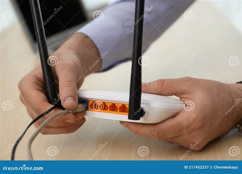 Man Connecting Cable To Router At Wooden Table Closeup Wireless Internet Communication Stock