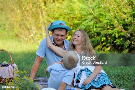 행복 한 가족 재미와 여름 날에 공원에서 앉아 노는 엄마는 아빠를 여자의 모자에 넣고 아들과 웃음을 했습니다 자연에서 가족 소풍 초상화 수평 보기 T 셔츠에 대한 스톡 사진