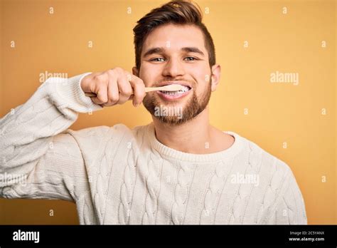 Young Handsome Caucasian Man Brushing His Teeth Using Tooth Brush And Oral Paste Cleaning Teeth