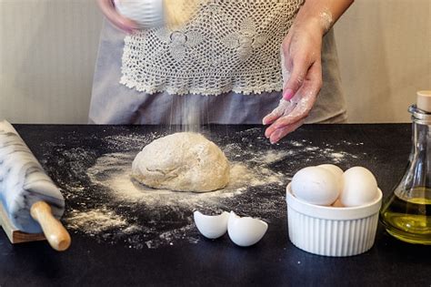 유리 그릇에서 밀가루를 추가 하 여 검은 나무 테이블에 여성 손으로 반죽을 만들기 반죽 계란 식물성 기름 밀가루 테이블 대리석에