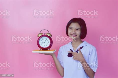 행복 한 아름 다운 젊은 아시아 여자 넣어 알람 시계 와 유니폼 분홍색 배경으로 그녀의 손에 책 Final Round에 대한 스톡 사진 및 기타 이미지 Istock