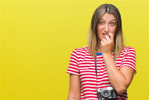 격리 된 배경에 강조 하 고 손톱을 물어 뜯고 입에 손을 긴장을 찾고 빈티지 사진 카메라를 사용 하 여 사진을 찍는 젊은 아름 다운 여자 불안 문제입니다 감정에 대한 스톡