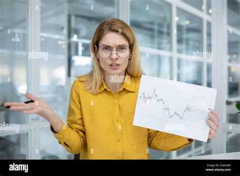 Businesswoman Expressing Confusion While Analyzing A Stock Market Graph During A Meeting In A