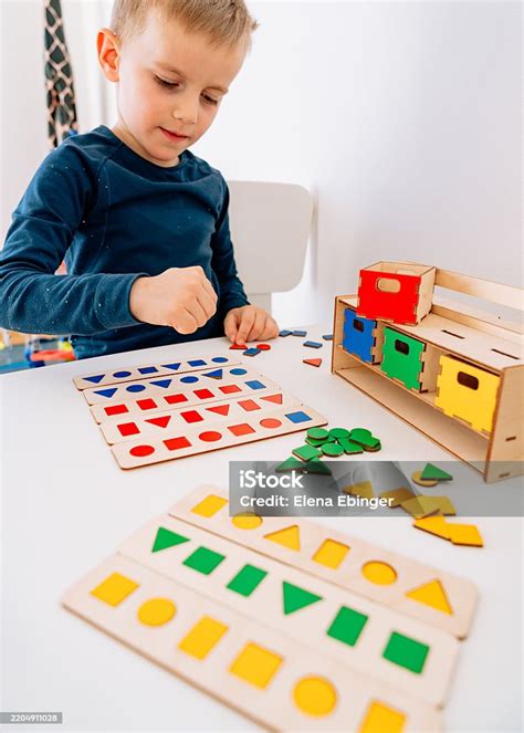 한 아이가 형형색색의 나무로 된 기하학적 도형을 테이블 위에 조심스럽게 올려놓고 모양과 색깔에 따라 분류한다 몬테소리에서 영감을 받은 훌륭한 학습 경험 Stem 주제에 대한