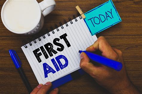 단어 쓰기 텍스트 응급 처치입니다 작은 치유의 연습에 대 한 비즈니스 개념 인하는 의료 훈련 남자에 대 한 필요가 마커 노트북 옷 핀 알림 나무 테이블 커피 컵을 들고 0