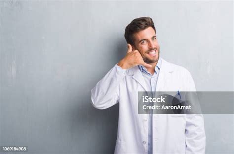 잘생긴 젊은 전문 남자 회색 그런 지 벽 입고 위에 흰색 코트 하 고 웃 고 손을와 같은 전화에 손가락 제스처를 전화 통신 개념 개념에 대한 스톡 사진 및 기타 이미지