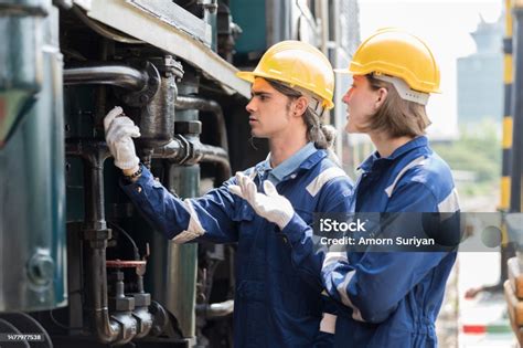 남성과 여성 엔지니어 유지 보수 기관차 엔진 기관차 수리 차고에서 안전 유니폼 헬멧 및 장갑을 착용 남성과 여성 철도 엔지니어는