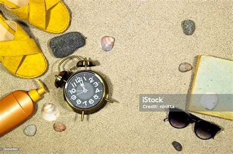 슬리퍼와 우유 바디 병 선글라스와 돌 조개 및 모래 여름 컨셉에 12시를 보여주는 알람 시계가있는 오래된 책 0명에 대한 스톡