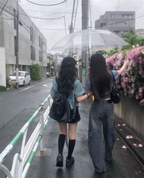 Two Girls Walking Down The Street In The Rain