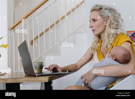 Woman Carrying Baby In Arm Working From Home Stock Photo Alamy